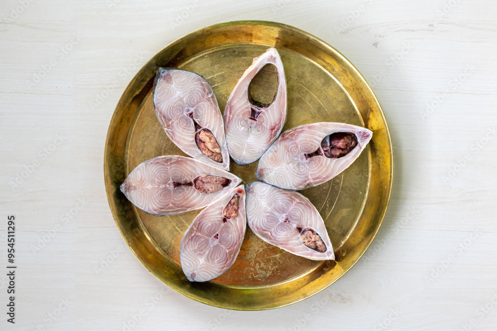 Slices of fresh raw hilsa fish on brass plate, ready for cooking. The ...
