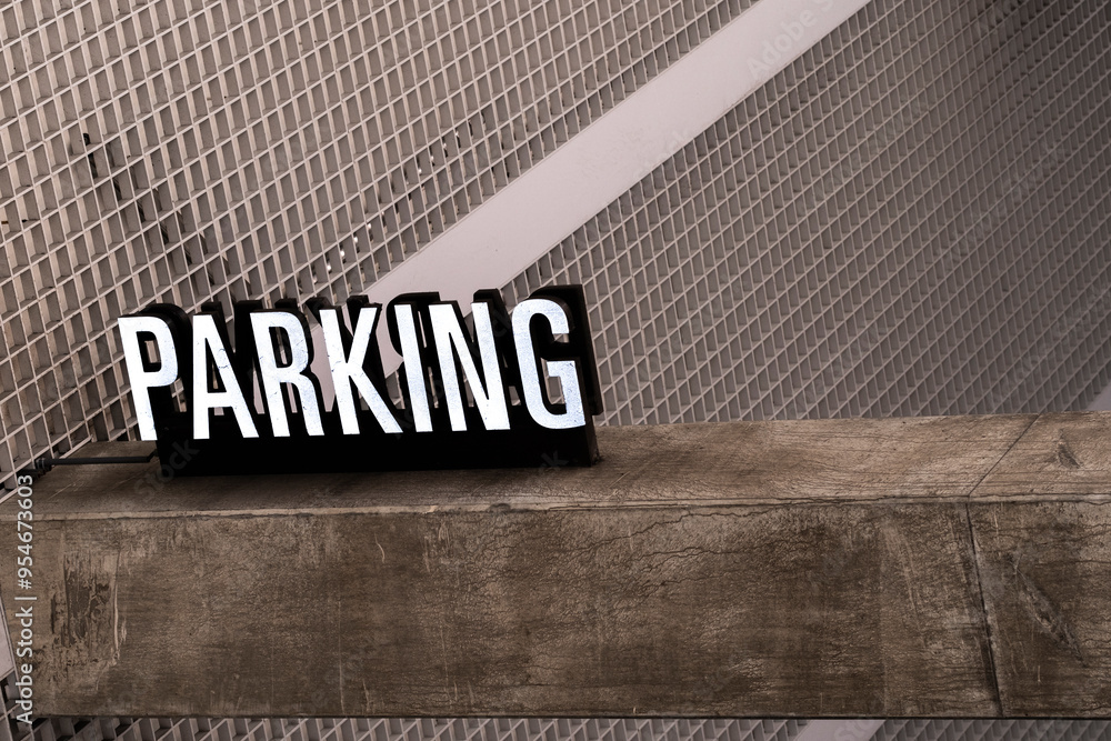 This image shows a 'Parking' sign against a metal mesh background with ...