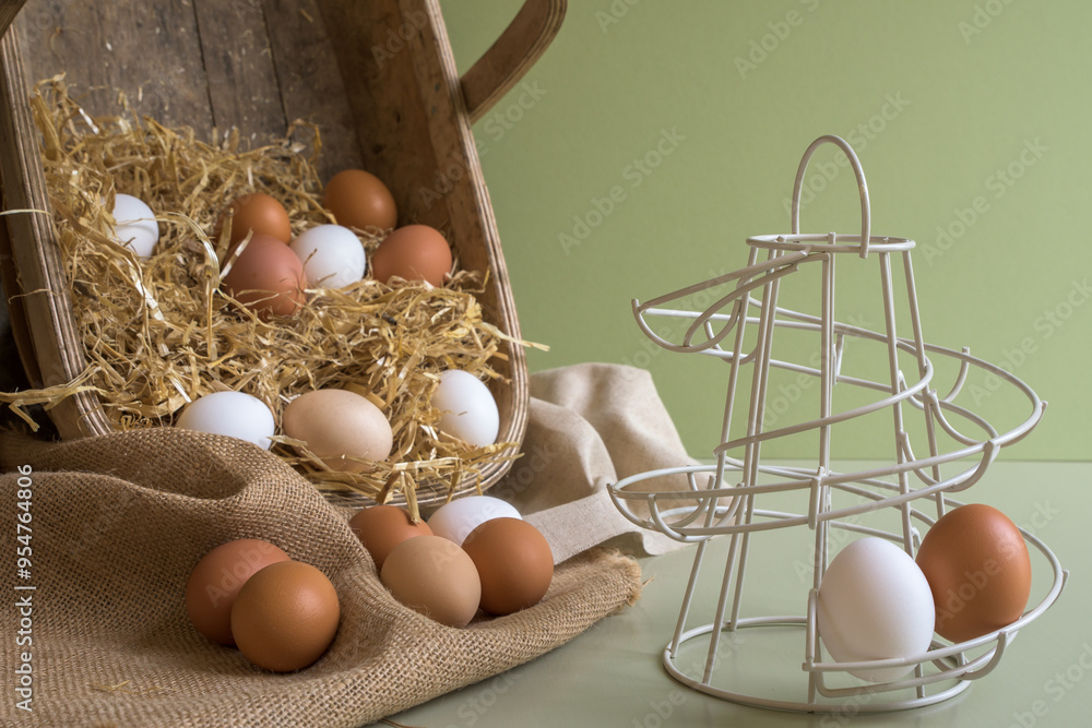 Farm chicken eggs stacked into a wire tower. Basket filled with straw ...