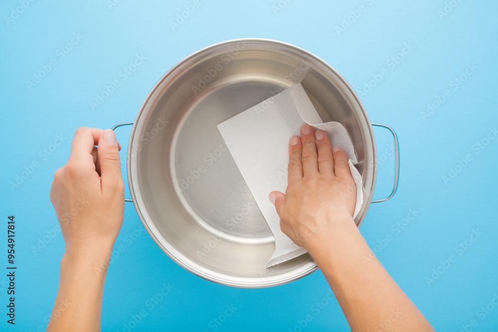 Young adult woman hand wiping stainless cooking pot with dry white ...