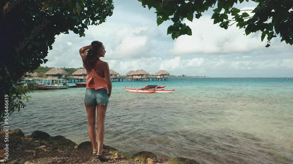 Young woman is enjoying the view of a luxury resort in bora bora, french polynesia. The ...