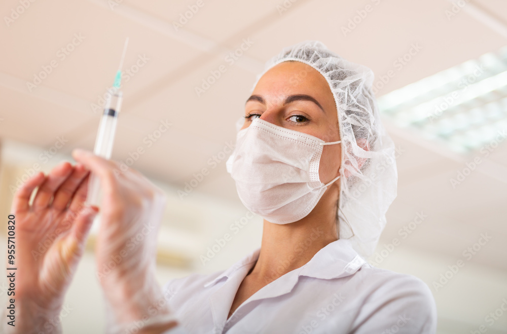 Young nurse in the treatment room prepares a syringe for injection ...