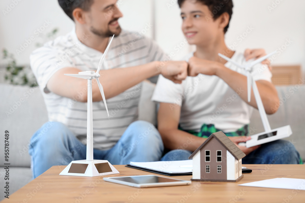 Wind turbine with house model on table of father and teenage son ...