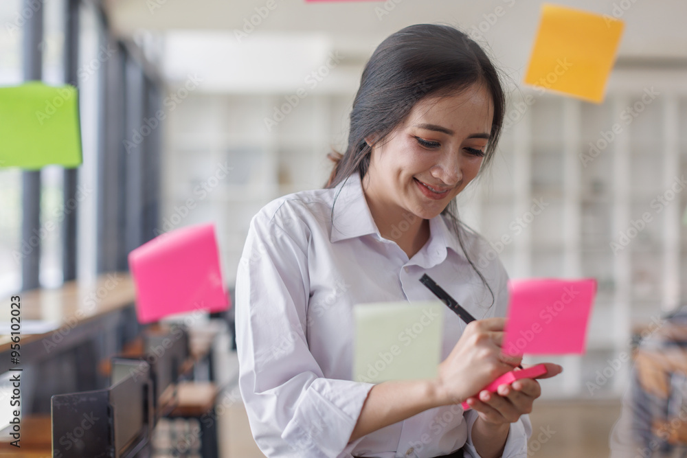 Young Serious asian Creative team use post it notes to share idea ...