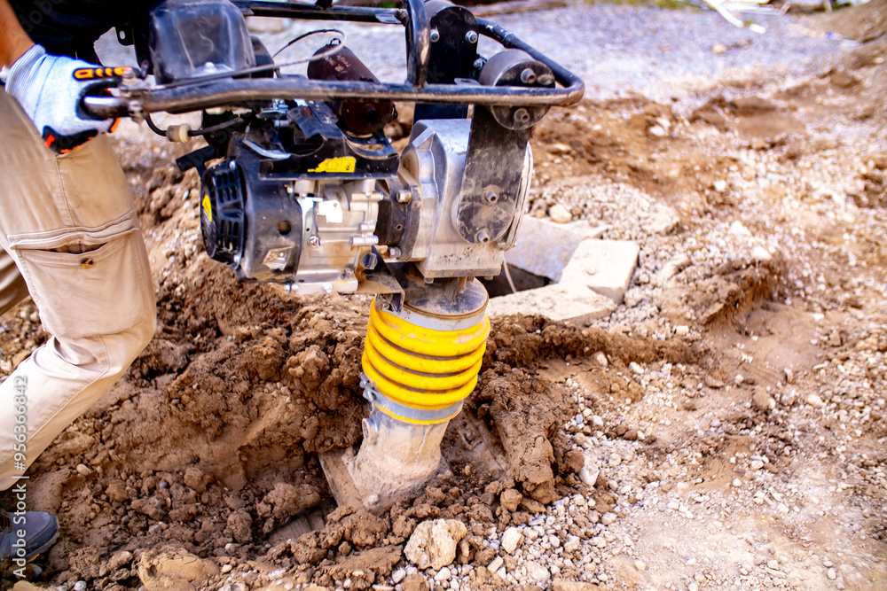 Compacting the soil. A compacting machine in the process of manual ...