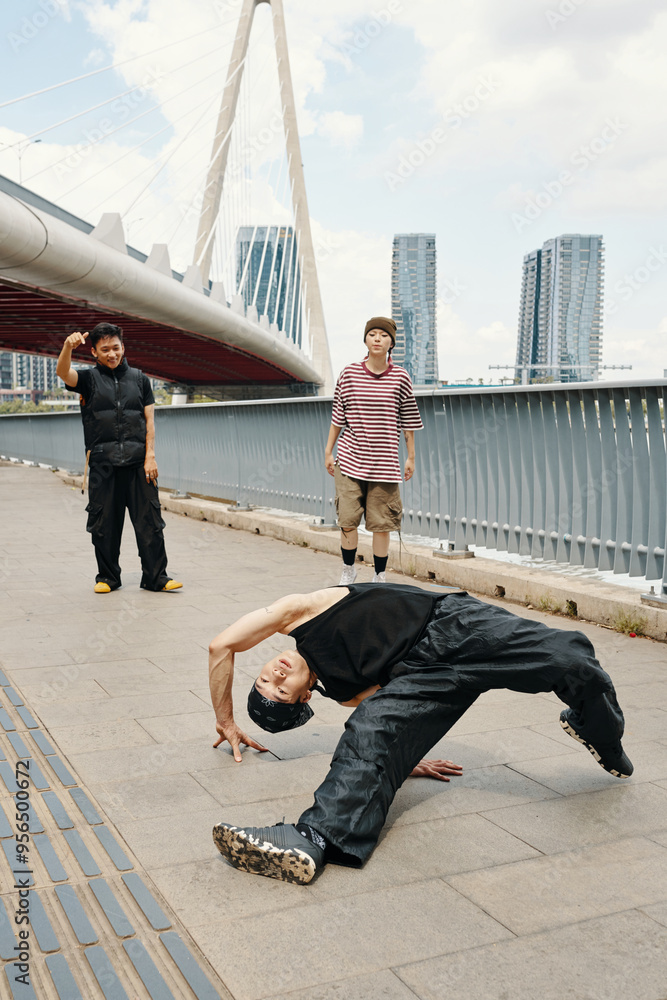 Group of young men performing breakdance moves on urban bridge with ...