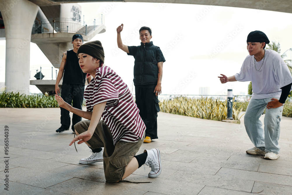 Group of friends breakdancing in urban setting under overpass engaging ...
