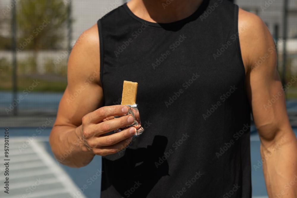 Sports man eating energy bar. Muscular athlete snacks on protein bar ...