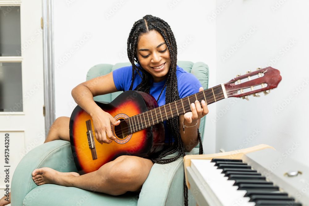 Medium shot of a young black girl with braids playing a flamenco guitar ...