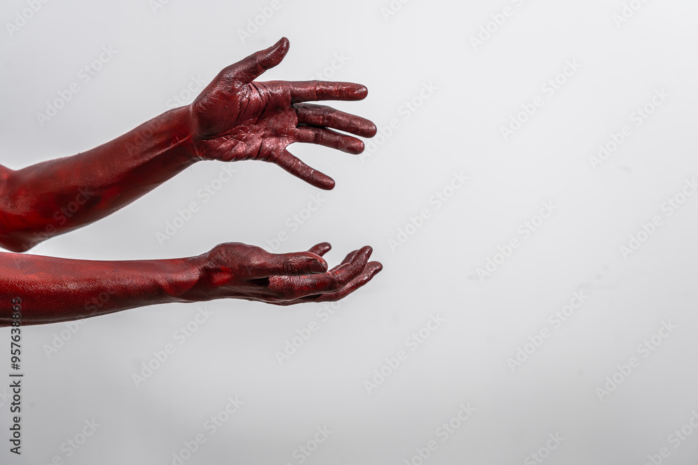 A terrifying red demon hand, reaching out menacingly on white studio ...