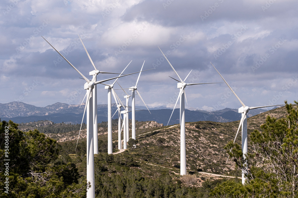 This image shows multiple wind turbines set against a dramatic cloudy ...