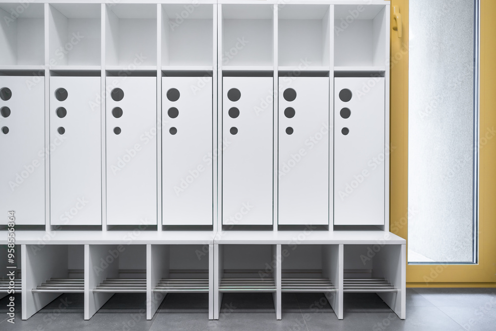 White lockers with circular cutout handles are aligned in a modern ...