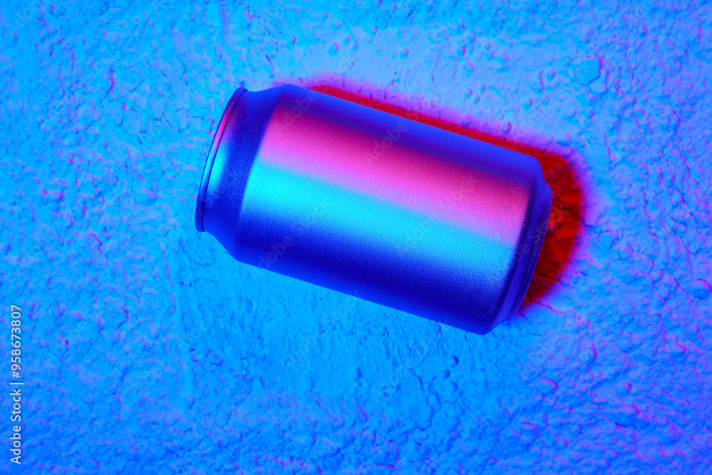 Aluminum can against textured surface in neon blue light, creating ...