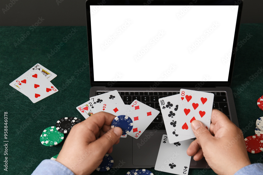 Online poker. Man holding playing cards and chip at green table with ...