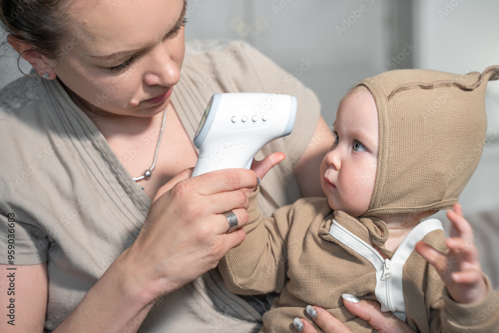 Mom measures body temperature baby by electronic thermometer. Sick child with high temperature ...