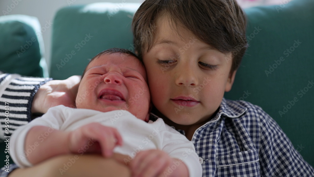Young boy comforting crying newborn sibling up close, illustrating the ...