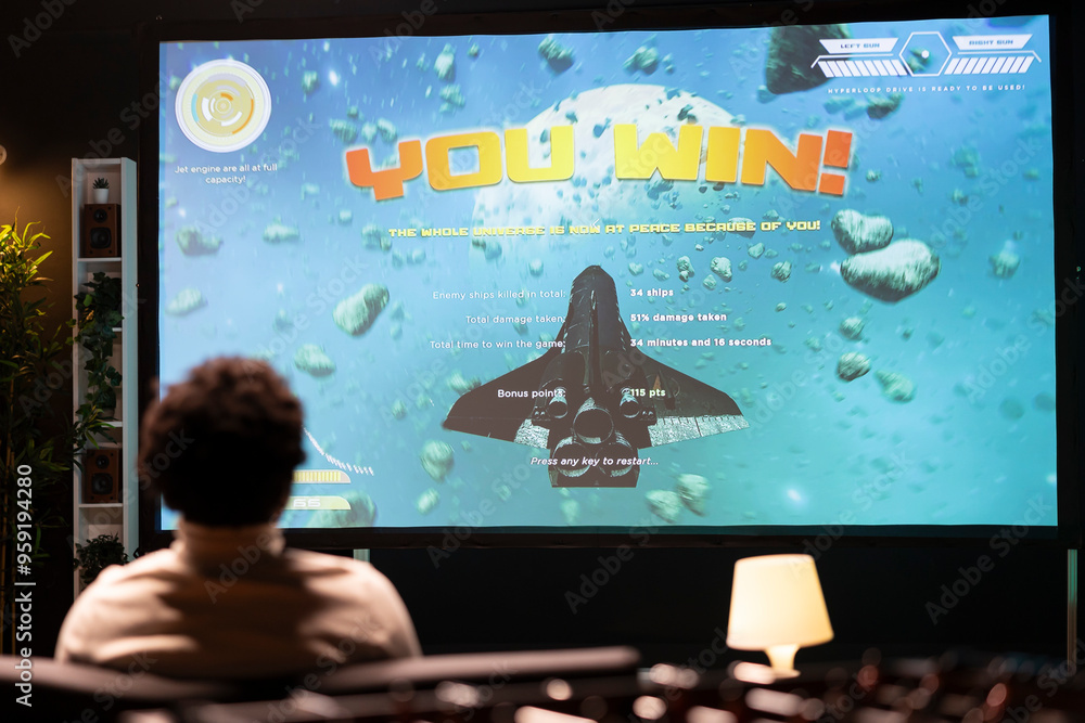 BIPOC man looking at winning screen of SF game on ultrawide smart TV ...