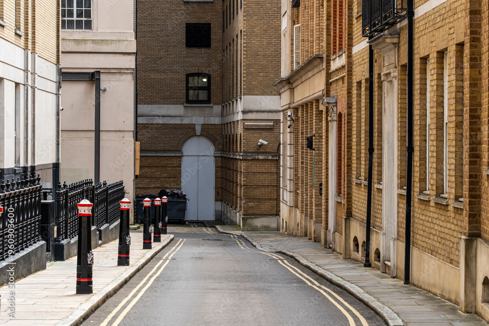 A quiet narrow alley between vintage brick buildings, representing the ...