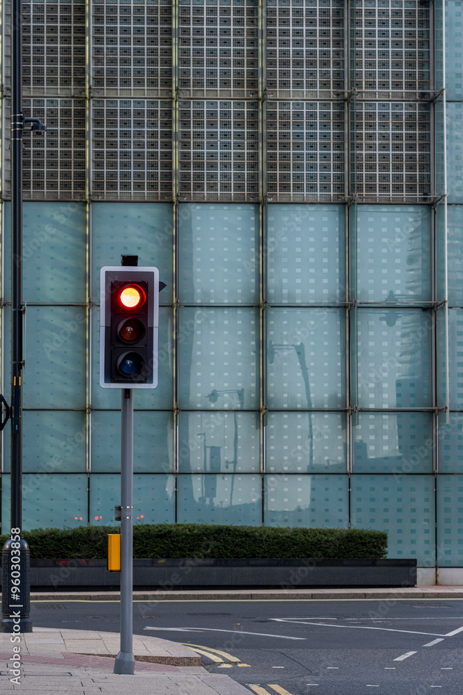 A red traffic light on a pole stands prominently in a modern city ...