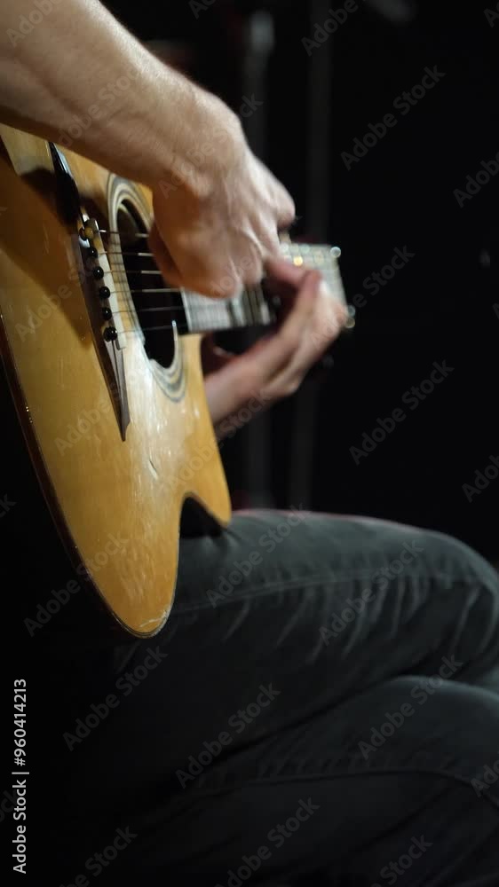 A guitarist playing an acoustic guitar during a live concert ...