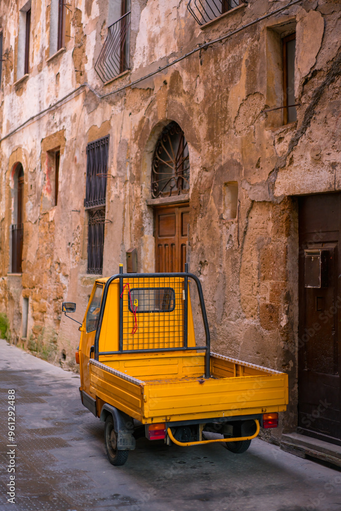 Iconic yellow Piaggio Ape three wheeler on an antique street of Italy ...