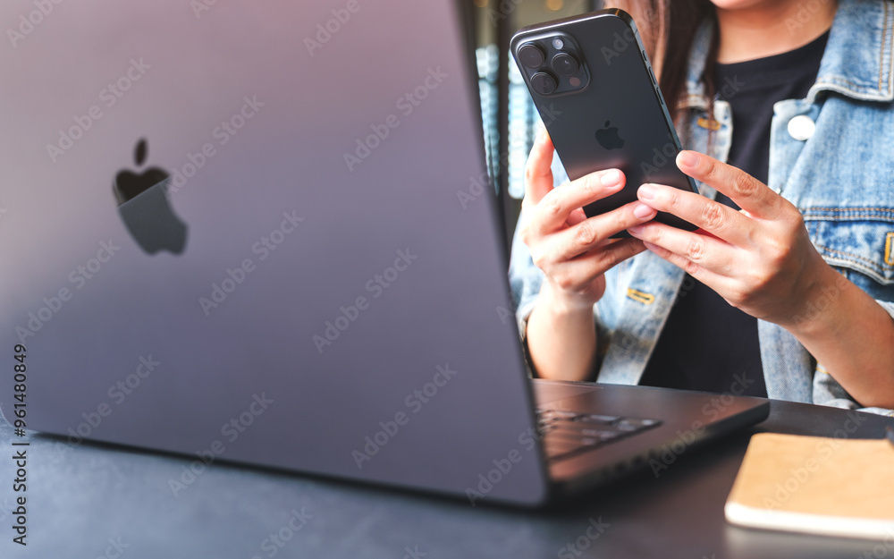 Aug 5th 2024 : A woman using Iphone 15 Pro max smartphone and laptop ...