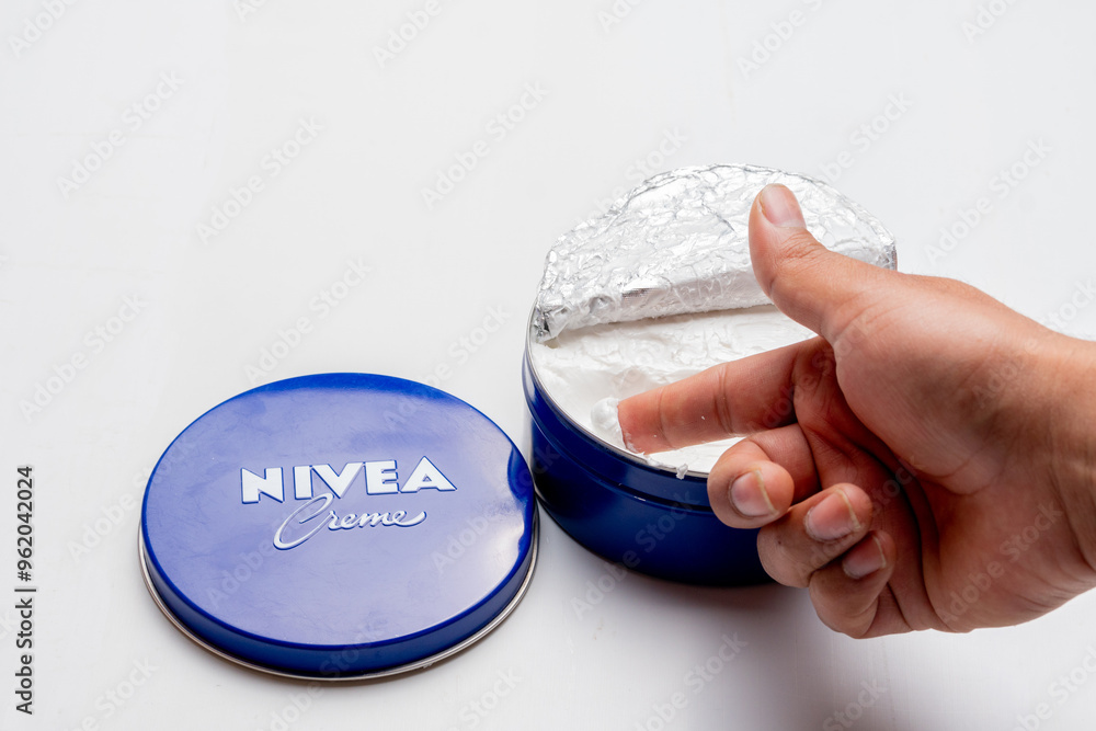 Close up of a man's hand smearing his finger with Nivea cream, cut out ...