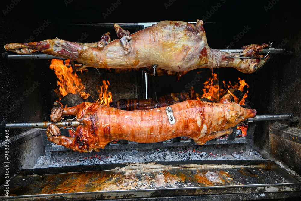 Whole lamb and pig are roasting on a spit over a fire pit Stock Photo ...