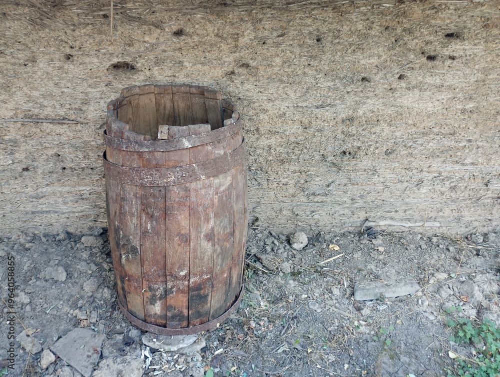 An old wooden broken barrel near an old clay plastered wall. A broken ...
