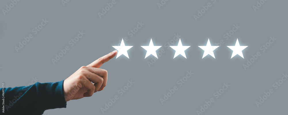 Hand pointing at five shining stars on a grey background, symbolizing ...