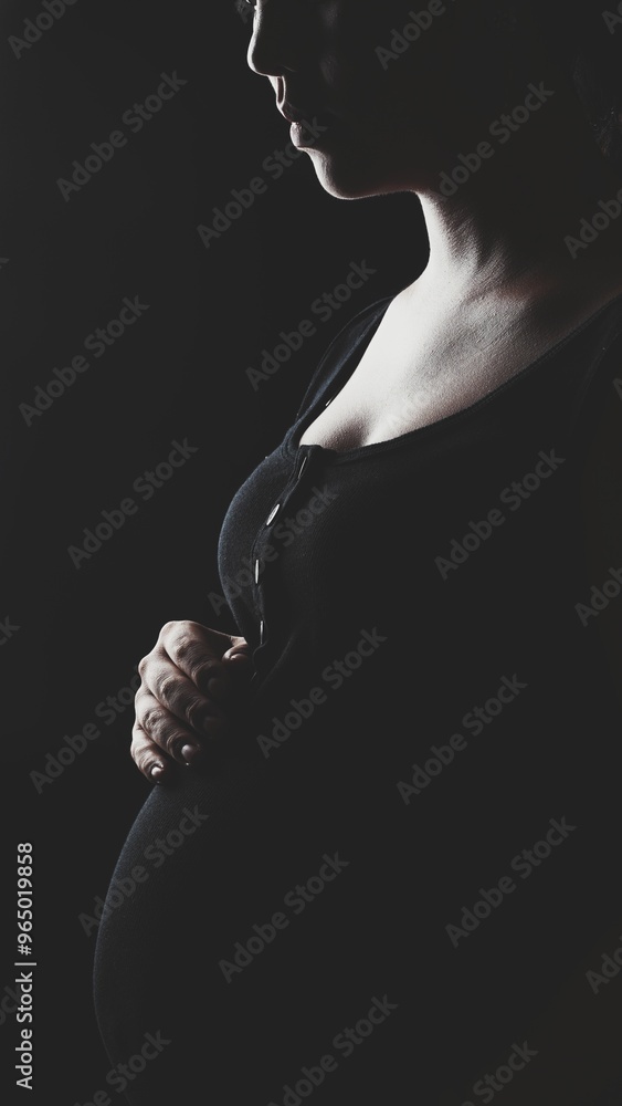 A low-key black and white sideways protrait of a pregnant asianwoman in ...