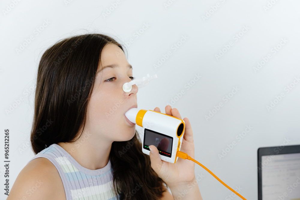 Girl testing breathing function by spirometry in doctors office ...