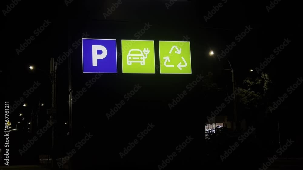 Brightly lit parking, electric vehicle charging, and recycling signs ...