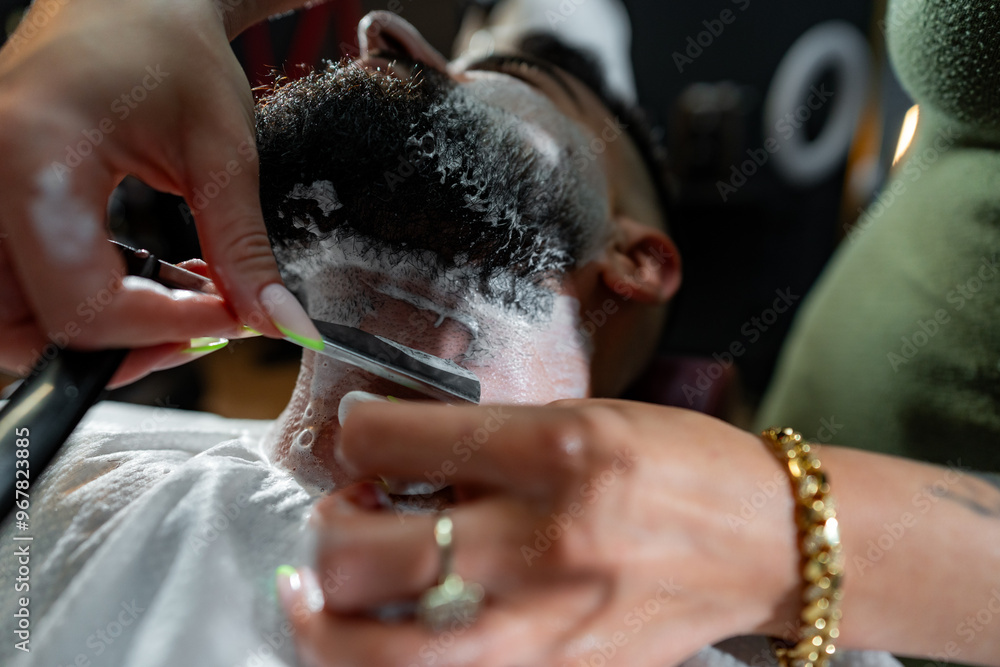 Barber carefully shaves under the neck with a straight razor, focusing ...