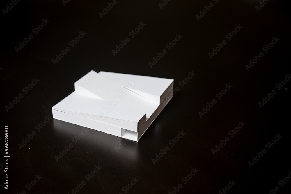 White scale model of a building with a pitched roof on a black ...