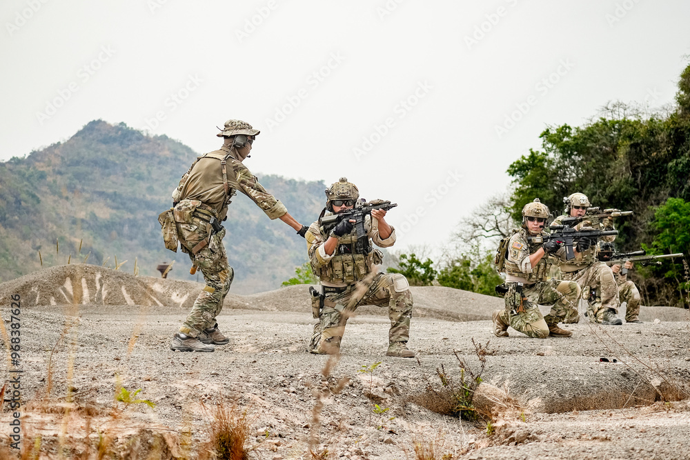 A group of military men in combat gear patrol in the middle of a desert ...