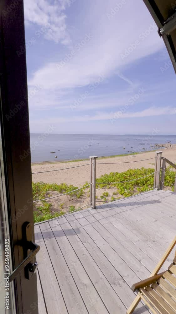 A woman lounges comfortably on a bed, gazing out of large open windows ...