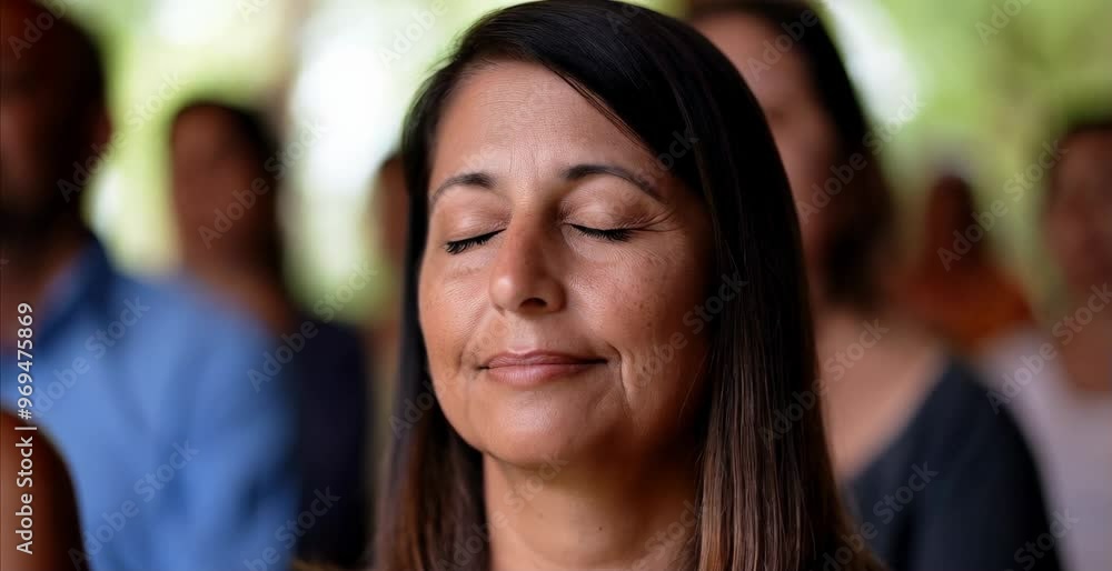 Calm woman piecefully sits with her eyes closed and meditates listening ...