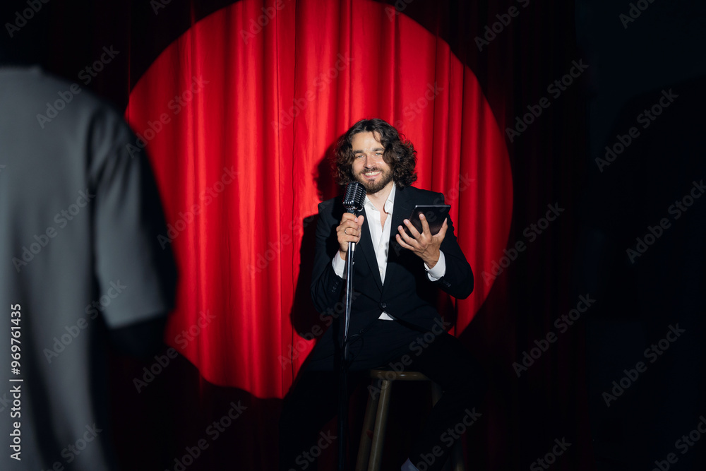 Stand up comedian on stage. Young man talks joke into microphone or ...