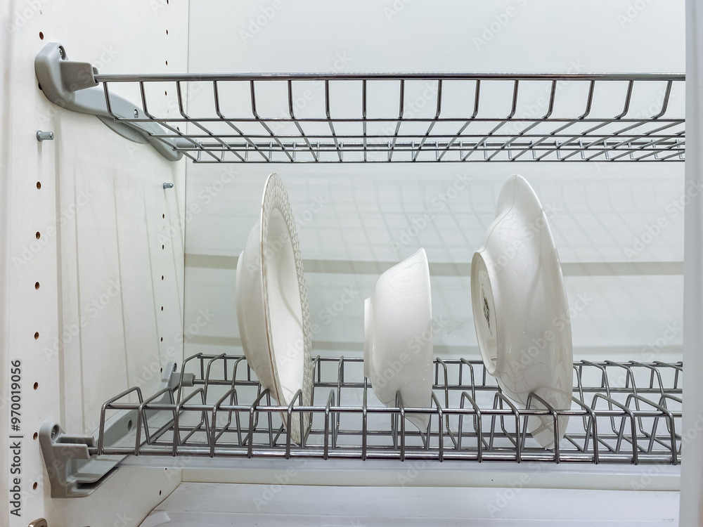 A dish rack that is holding various plates and bowls neatly arranged on ...