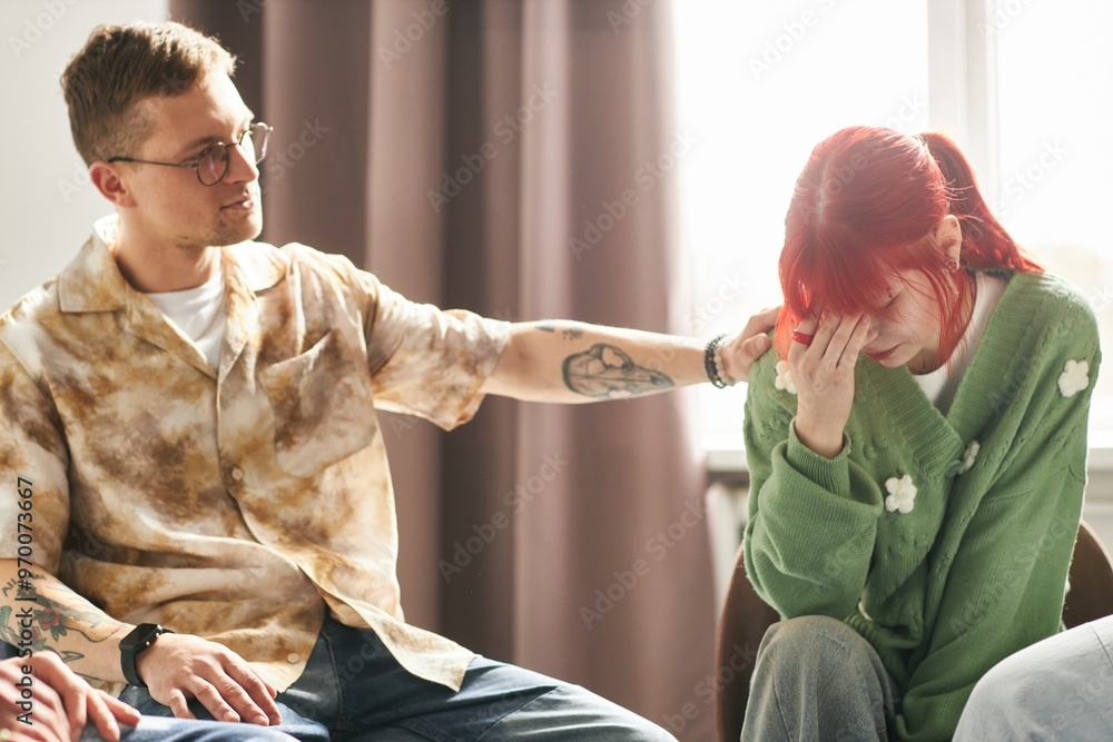 Young man with tattoos comforts young woman who is visibly upset ...