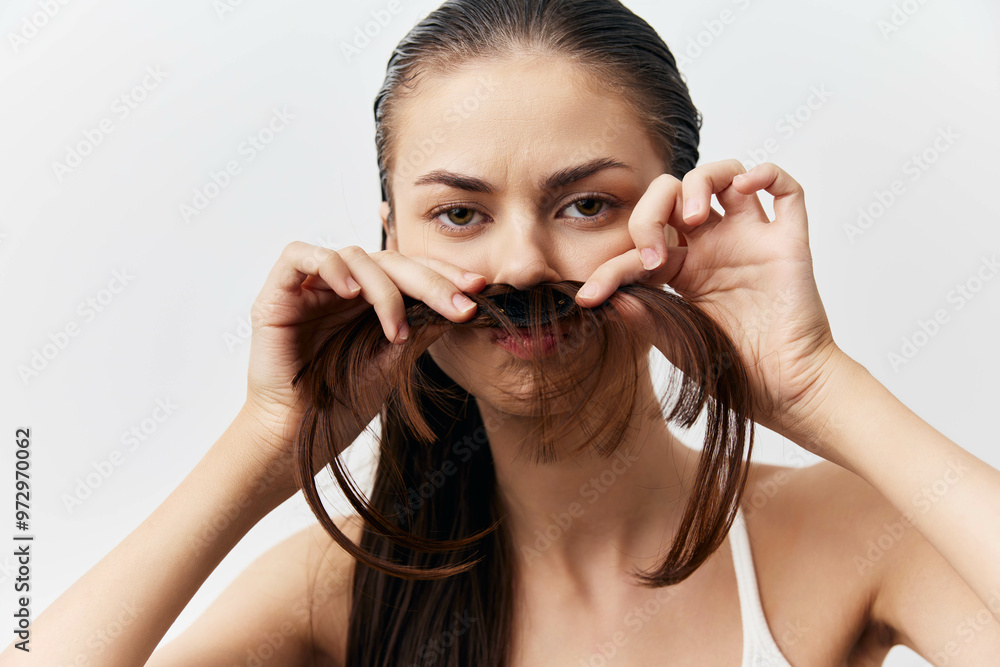 Woman playfully holding hair to create a mustache effect, expressing ...