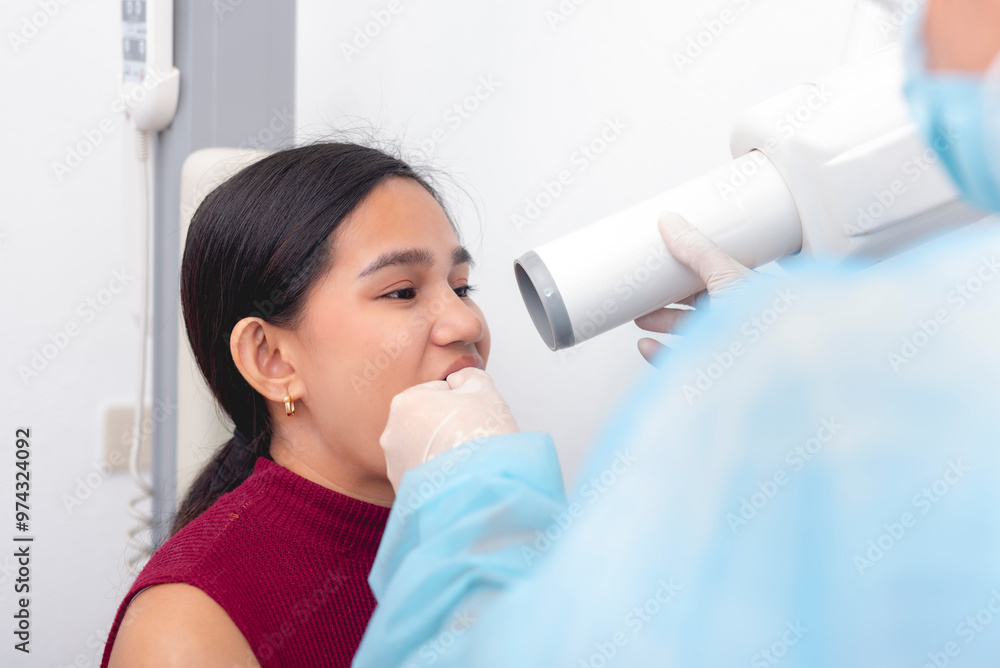 A dentist taking an X-ray of a patient's teeth. The patient holds a ...