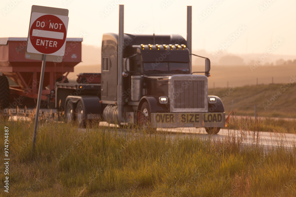 Golden hour captures a majestic semi-truck with 'OVERSIZE LOAD' signage ...