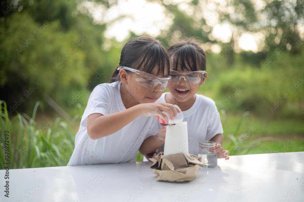 Two young girls excitedly play with a small volcano experiment ...