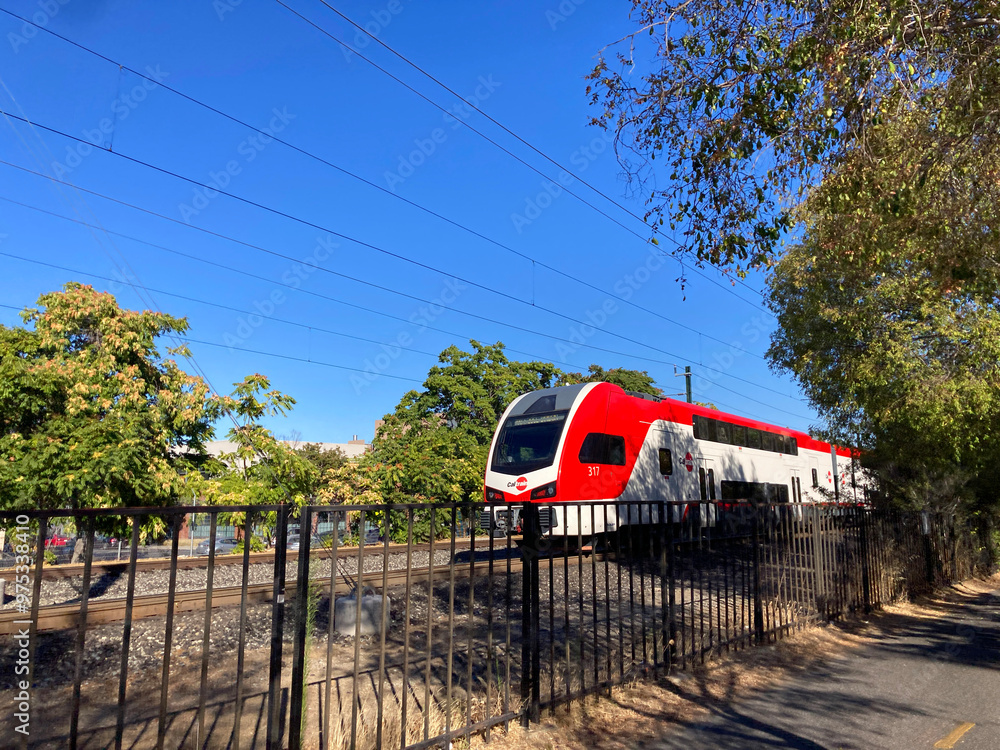 Double deck electric Caltrain commuter train Stadler KISS moves along a ...
