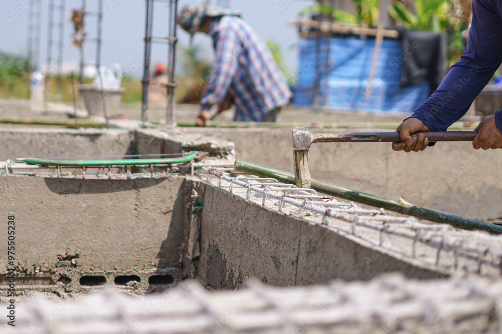 Construction worker hammering a concrete form at a building site ...