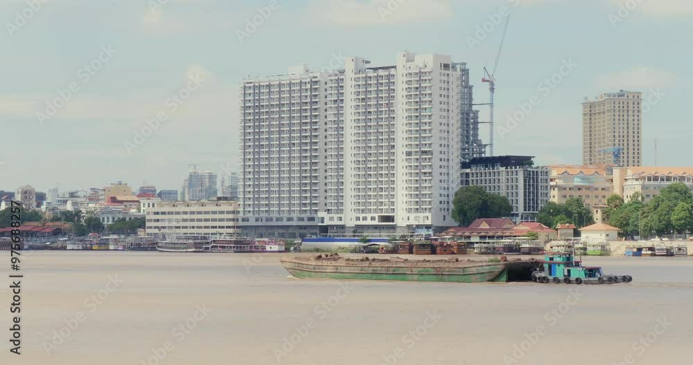 back view of a small tugboat pushes an empty barge downstream, with the ...