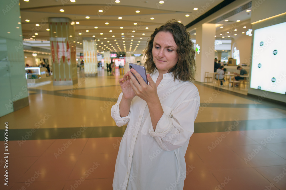 Person using smartphone in a modern shopping mall. Indoor candid ...