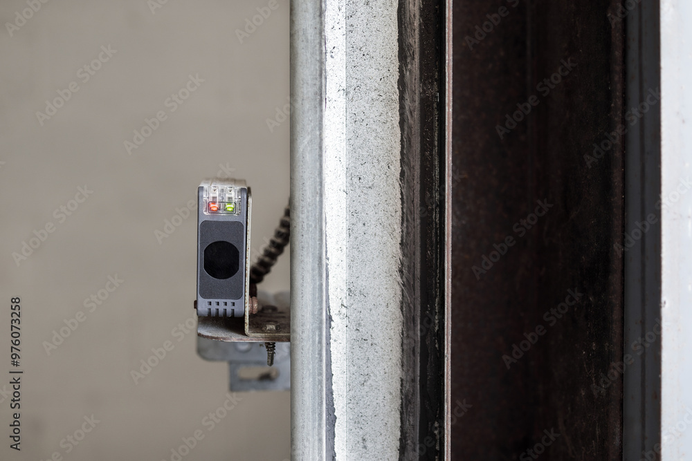 Garage gate sensor mounted on wall. Close up of photoelectric sensor ...